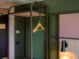 Um quarto com um cabide de madeira pendurado, uma luminária de parede preta e uma parede verde.