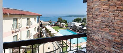 Uma varanda com vista para uma piscina, cadeiras de descanso e um muro de tijolos.