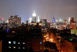 Paisagem urbana noturna com edifícios iluminados e um arranha-céu imponente.