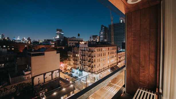 Vista noturna da cidade a partir de um ponto alto, com edifícios iluminados e ruas visíveis abaixo.