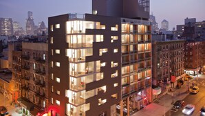 Um edifício urbano de vários andares com design moderno, com varandas e grandes janelas.