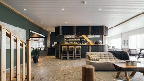 Uma sala de estar ampla com bar, assentos e escada.