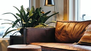 Uma sala de estar moderna com um sofá de couro, um banquinho de madeira e uma planta em vaso.