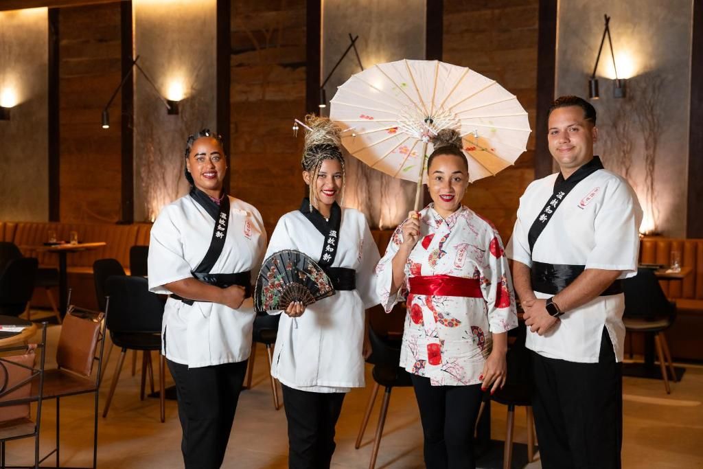 Um grupo de pessoas vestindo trajes típicos em um interior moderno com detalhes em madeira e iluminação suave.