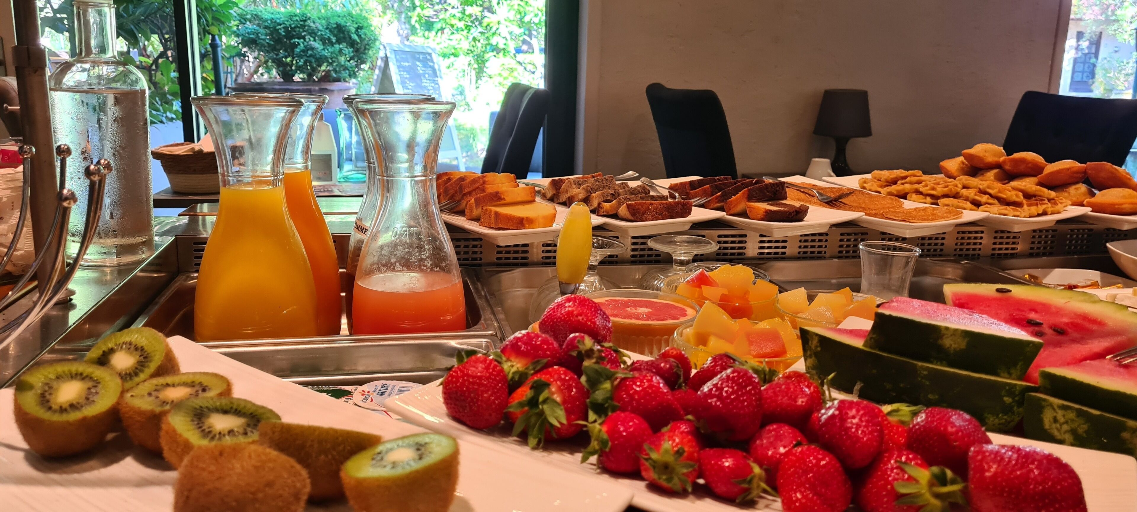 Buffet de café da manhã com frutas, sucos e pâtisseries.