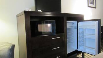 Quarto compacto com TV integrada e frigorífico.