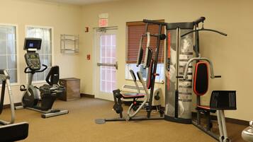 Centro de ginástica com equipamentos de cardio, aparelhos de musculação e um espelho.