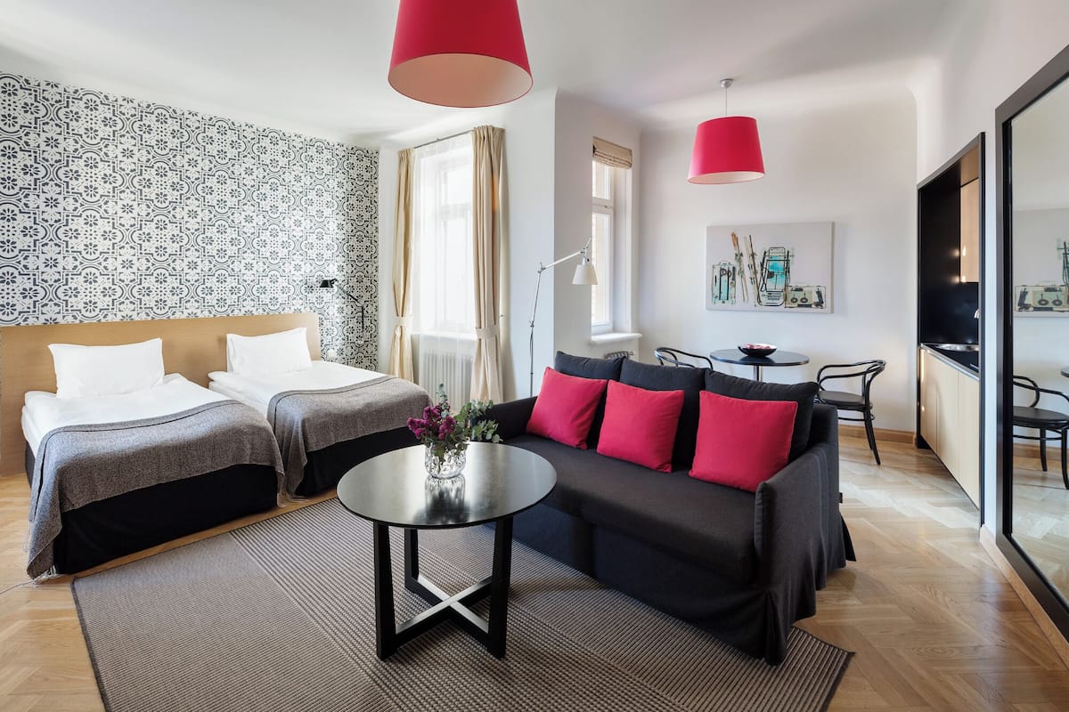 Quarto de hotel com duas camas, um sofá, uma mesinha e uma área de refeições.