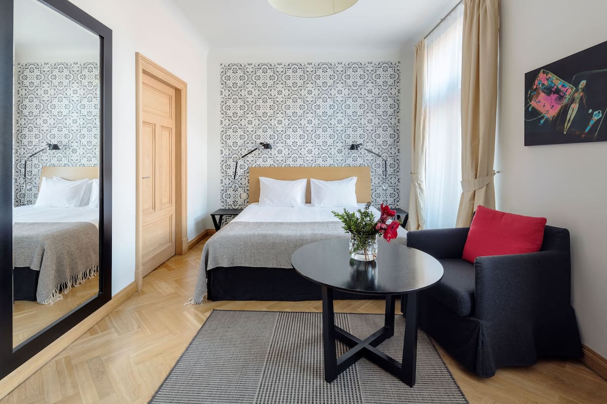 Quarto de hotel com cama, sofá, mesa e espelho.