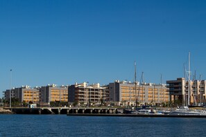 Uma marina com barcos e uma fileira de edifícios altos com varandas.