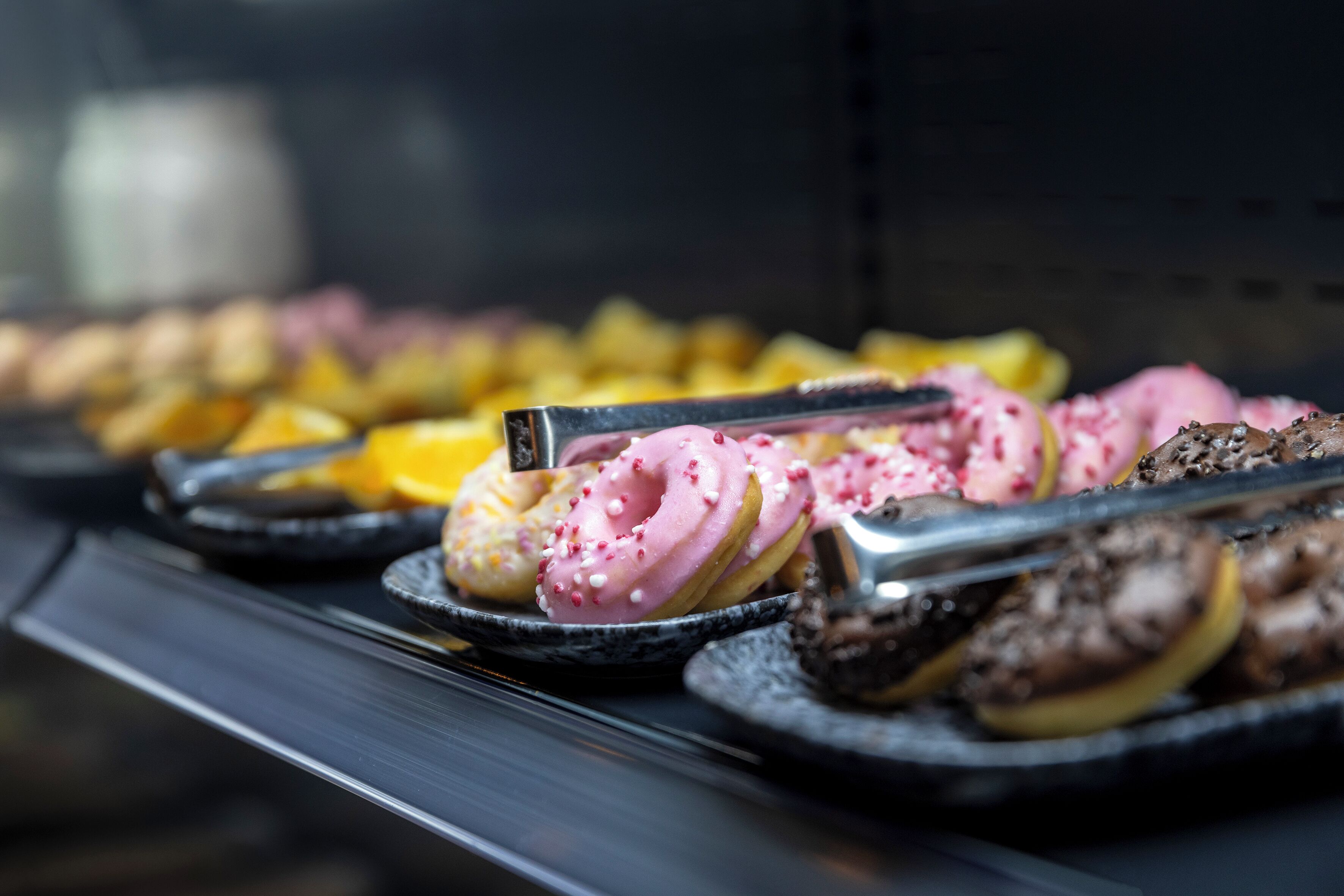 Diversidade de donuts em bandejas de exposição.