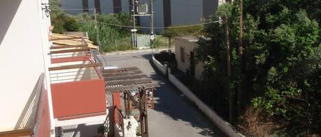 Uma rua estreita com edifícios em ambos os lados, uma pérgula de madeira e céu claro.