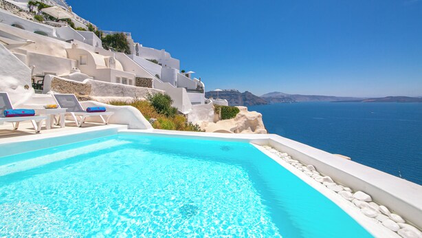 Área da piscina com edifícios brancos e vista para o mar.