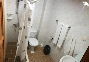 Casa de banho com chuveiro, sanita, bidé e lavatório.