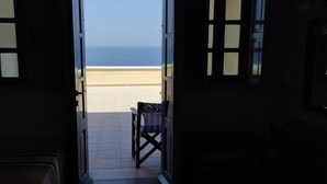 Uma porta aberta que dá para uma varanda com vista para o mar.