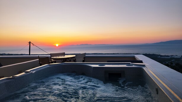 Piscina no terraço com vista para o pôr do sol sobre o mar.