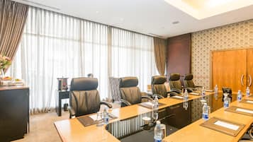Uma sala de conferências com uma mesa comprida, várias cadeiras e garrafas de água.