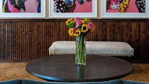Um quarto com uma mesa redonda, um vaso com flores e três quadros de cavalos na parede.