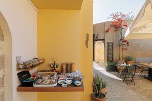 Uma área de refeições com mesa e cadeiras, uma prateleira com alimentos e um vaso de plantas.