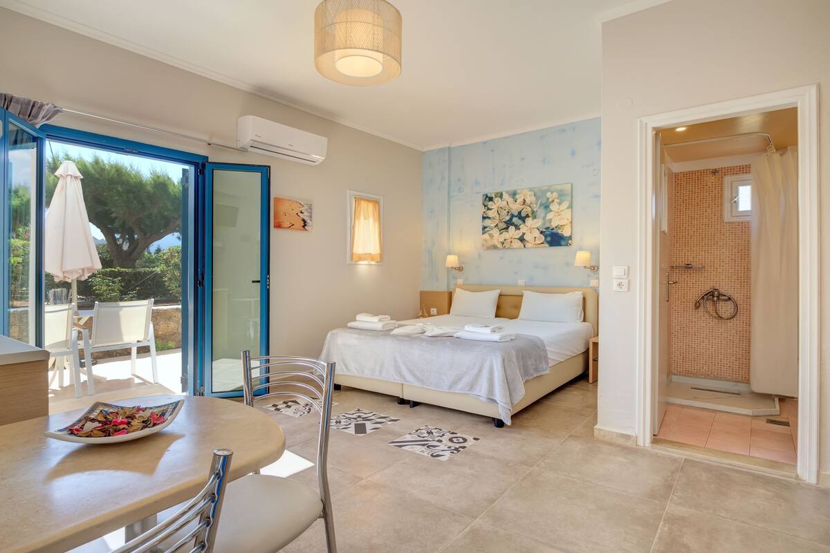 Quarto de hotel moderno com cama, área de refeições e chuveiro.