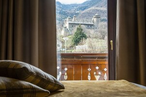 Quarto com vista para um castelo e montanhas.