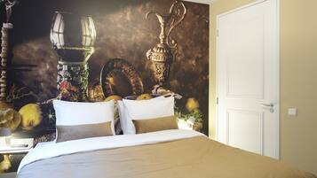 Quarto com cama, travesseiros, tapeçaria na parede e uma porta.
