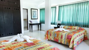 Quarto de hotel com duas camas, uma escrivaninha e um guarda-roupa.