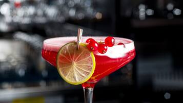 Coquetel em taça de martini com rodela de limão e frutas vermelhas.