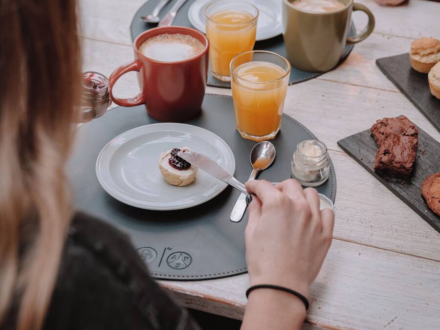 Uma mesa de jantar com um prato de comida, uma caneca e copos de suco de laranja.