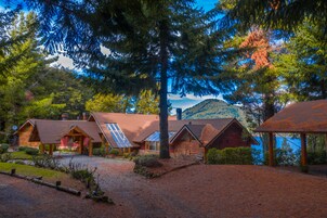 Uma pousada com várias cabanas, uma área de estar coberta e vista para uma montanha.