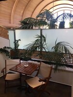 Uma mesa de madeira com duas cadeiras numa sala com teto arredondado e grandes janelas.