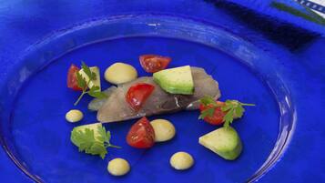 Um prato azul com prato de frutos do mar, um copo de água e um menu.