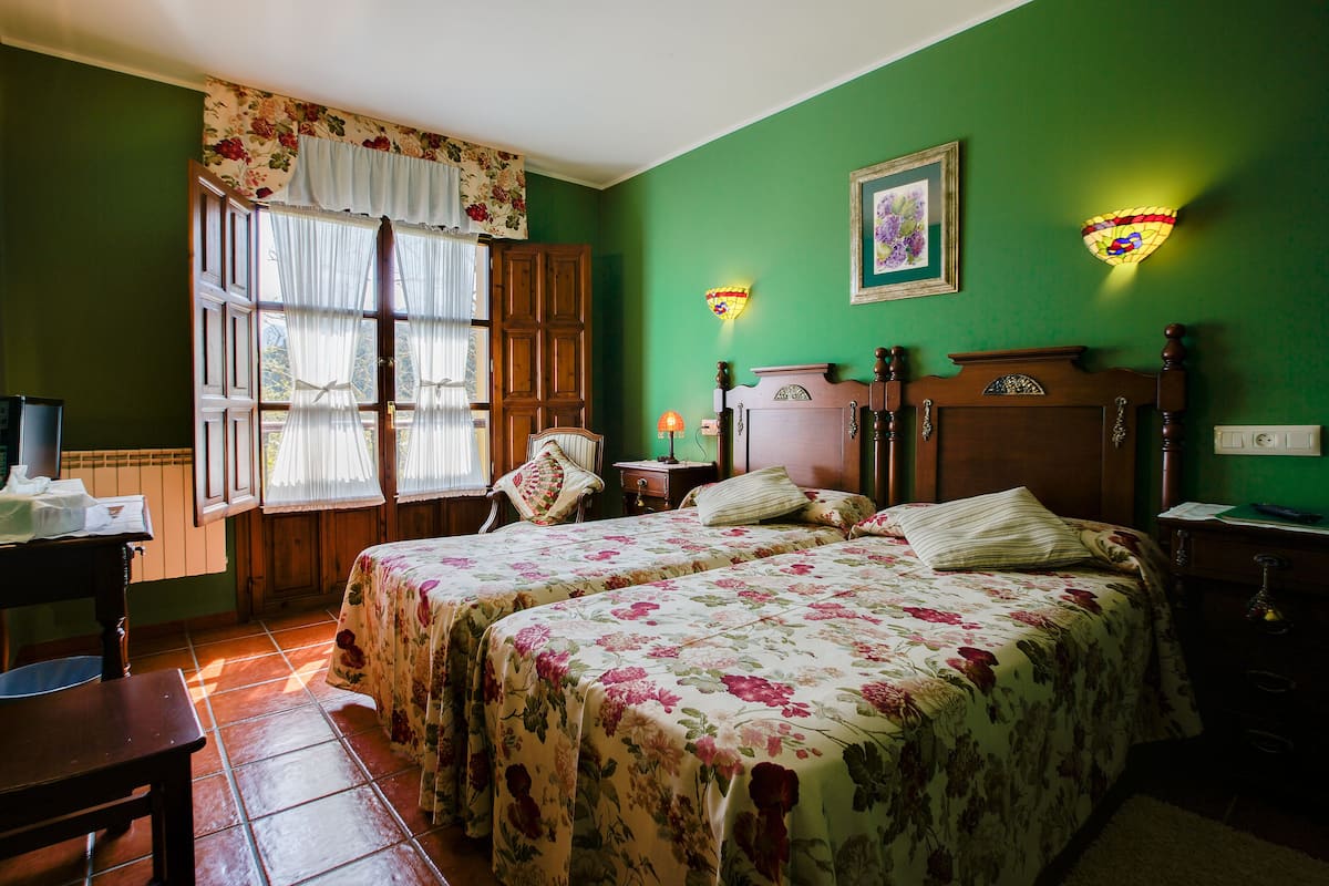 Quarto com duas camas, cabeceira de madeira, escrivaninha e uma cadeira.