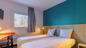 Quarto de hotel com duas camas, uma mesa e uma cadeira.