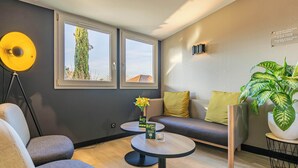Uma sala de estar moderna com um sofá, duas mesas redondas, um abajur e um vaso com planta.