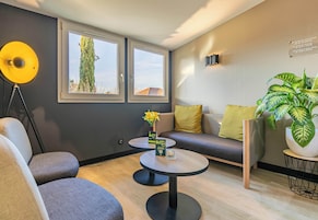 Uma sala de estar moderna com um sofá, duas mesas redondas, um abajur e um vaso com planta.