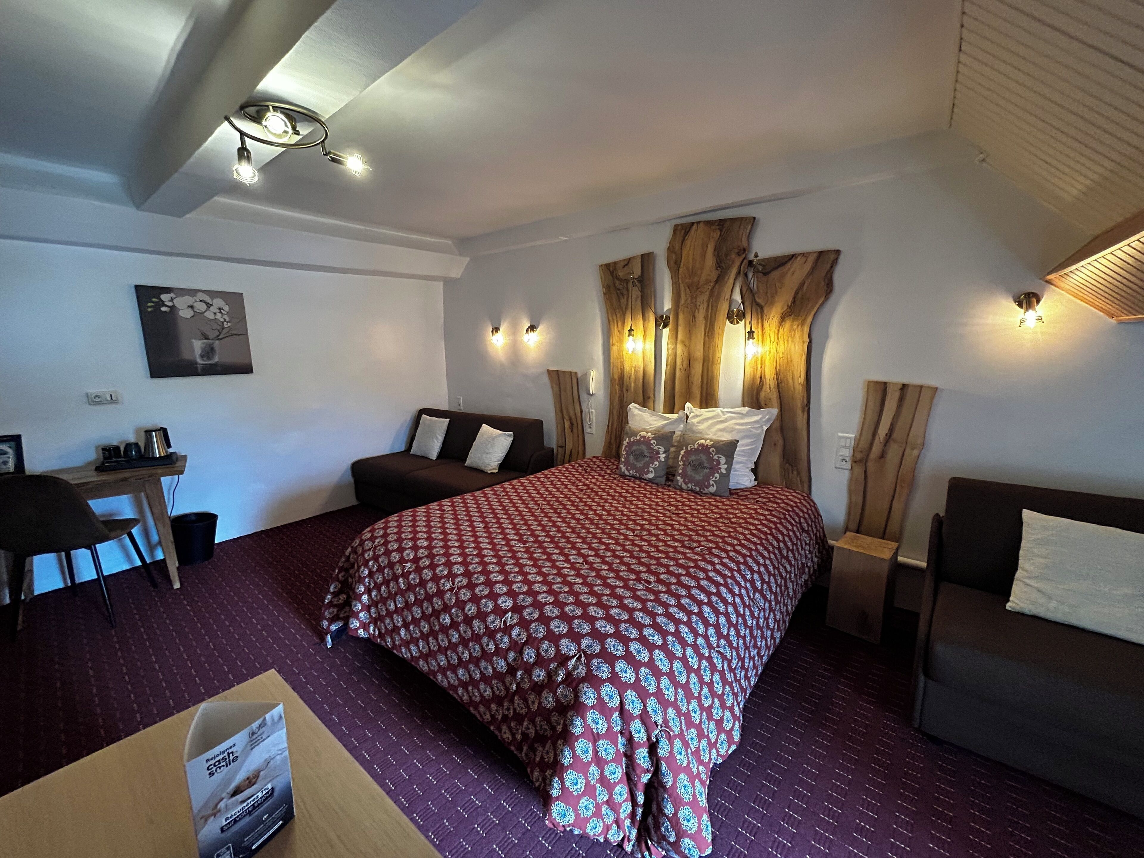 Quarto de hotel com cama, escrivaninha e cadeira.