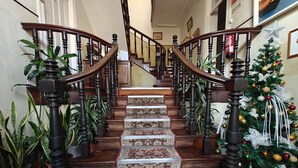 Uma escadaria imponente com grades de madeira ricamente decoradas e um patamar estofado.