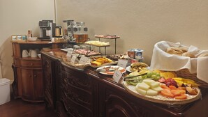 Buffet com diversas opções de alimentos, incluindo frutas, queijos e carnes.