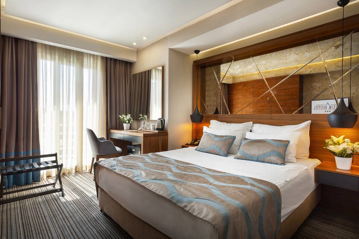 Quarto de hotel com uma cama grande, uma escrivaninha e uma cadeira.