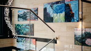 Uma escadaria com corrimãos de vidro e obras de arte nas paredes.