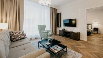 Uma sala de estar moderna com sofá, poltrona, mesa de centro, TV e lustre.