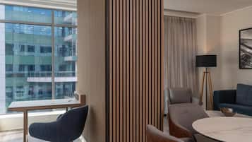 Quarto de hotel moderno com uma janela grande, uma mesa redonda e duas cadeiras.