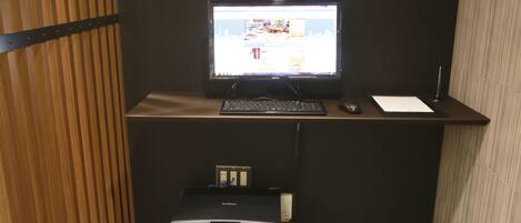 Uma escrivaninha com monitor, teclado, rato e impressora.