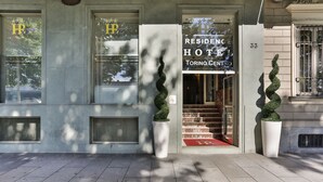 Entrada de um hotel com uma placa indicando "Residence Hotel Torino Centro" e uma escadaria que leva para o interior.