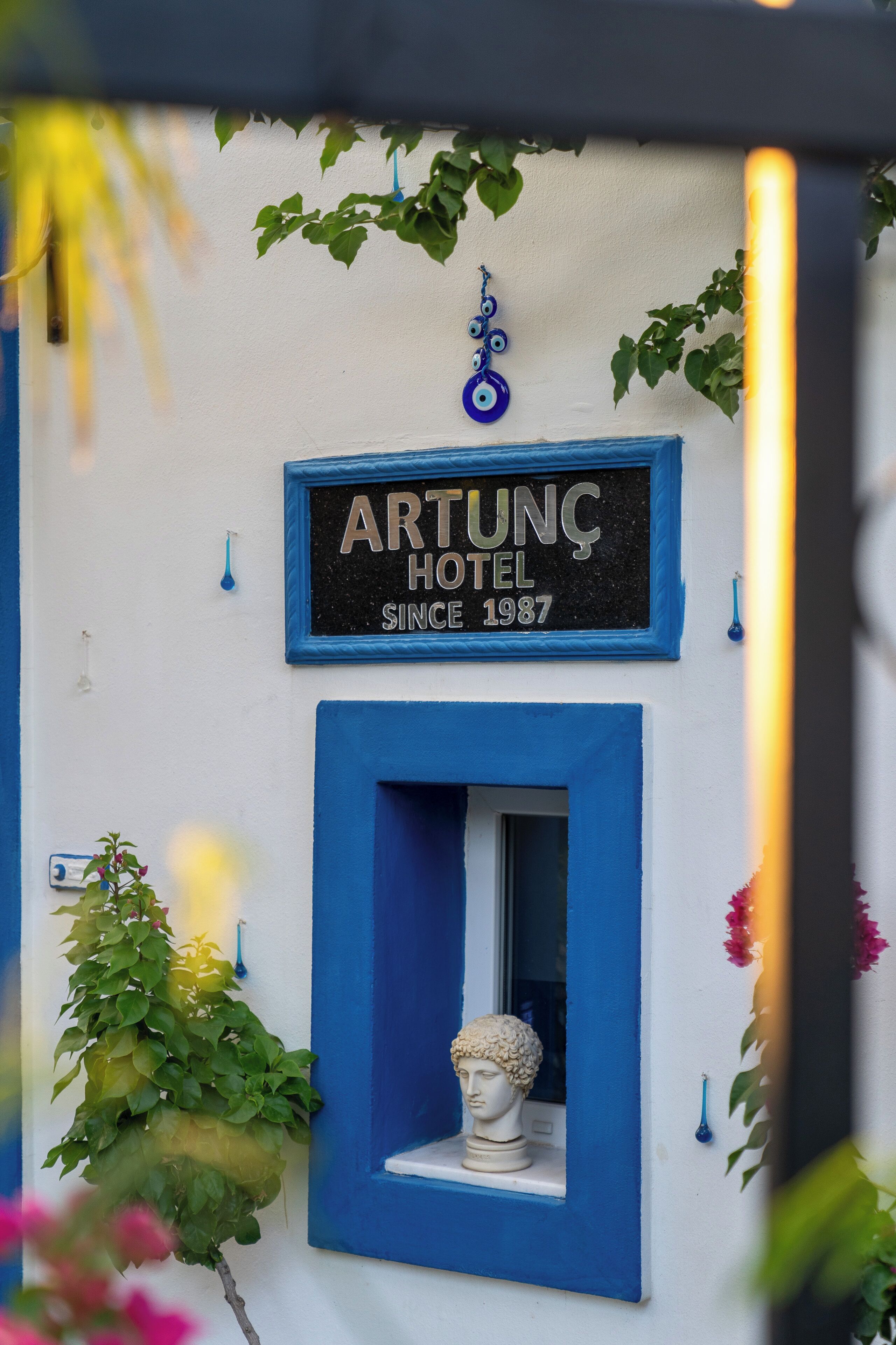 Placa de hotel com moldura azul e um busto em uma janela.