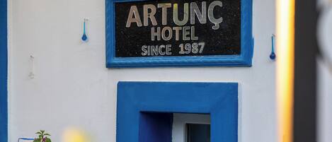 Placa de hotel com moldura azul e um busto em uma janela.