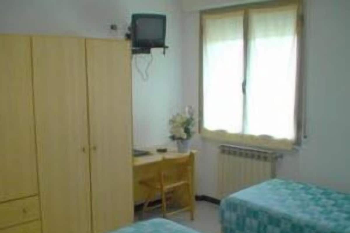 Um quarto com cama, escrivaninha e guarda-roupa.