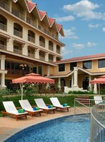 Um hotel com piscina, várias varandas e áreas de estar ao ar livre.