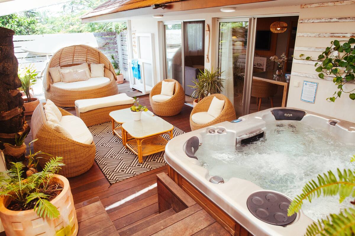 Uma área de spa com hidromassagem, cadeiras de vime e um deck de madeira.